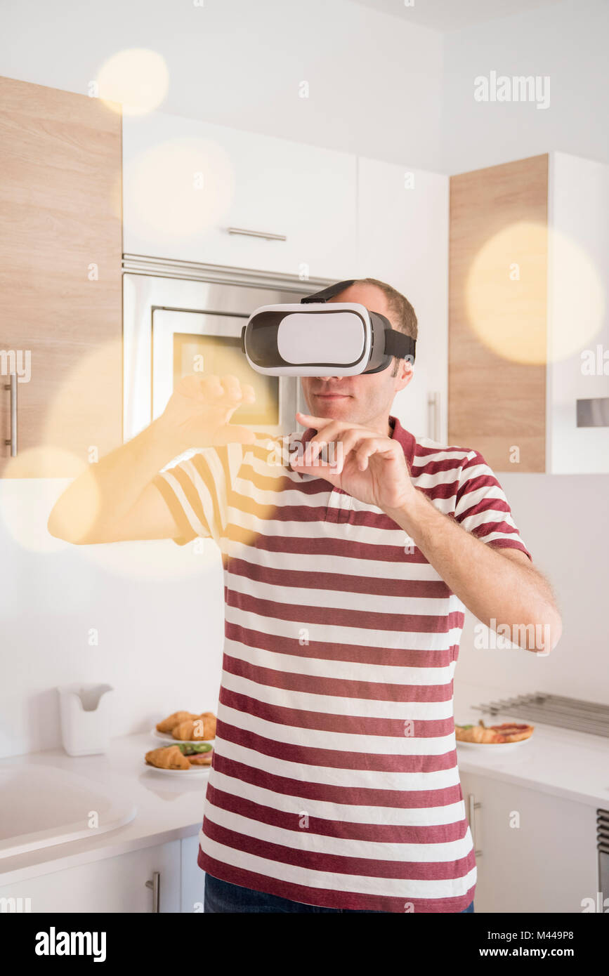 Mature man looking through virtual reality headset in kitchen Stock ...