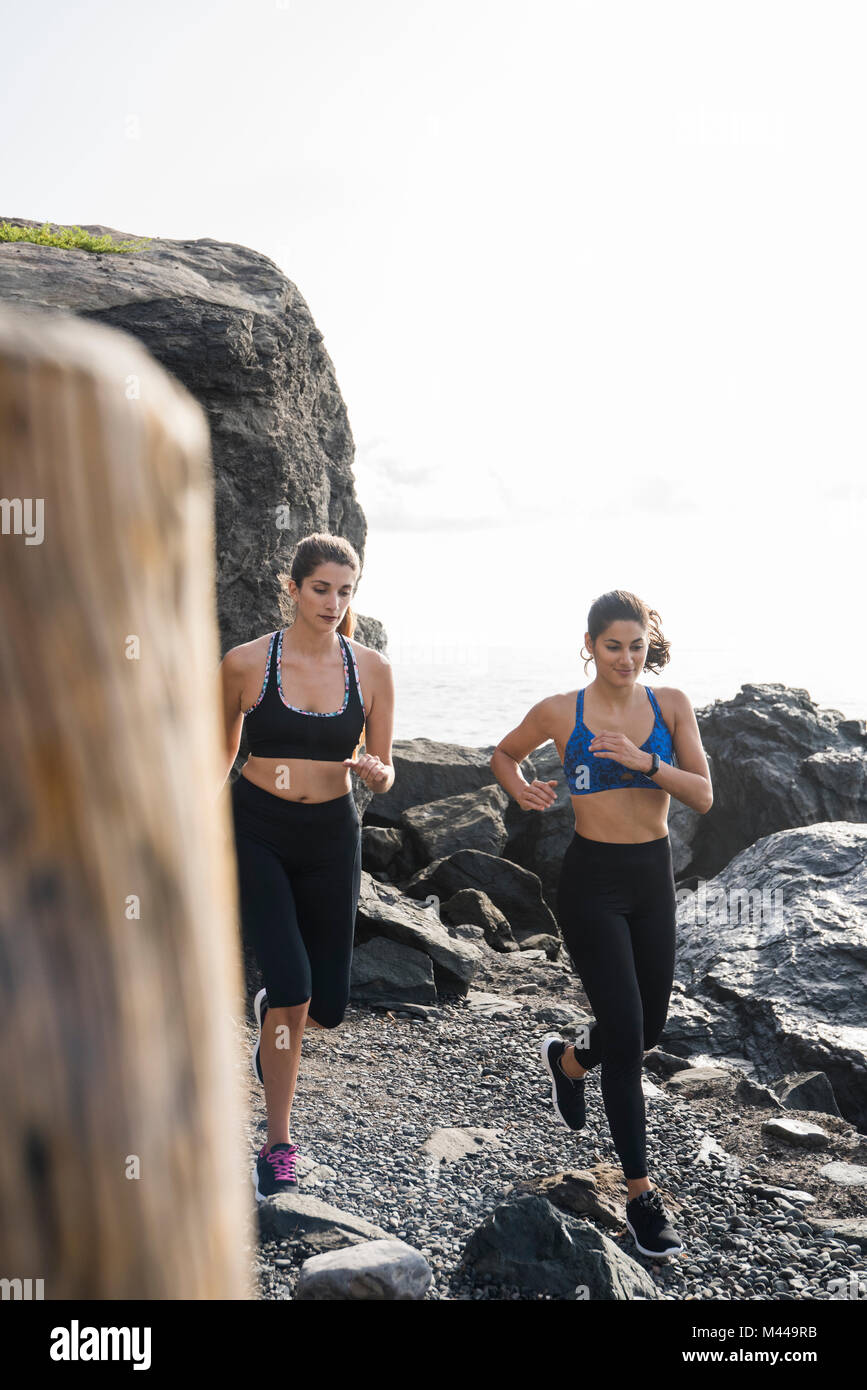 Two young female runners running on rocky beach, Las Palmas, Canary ...