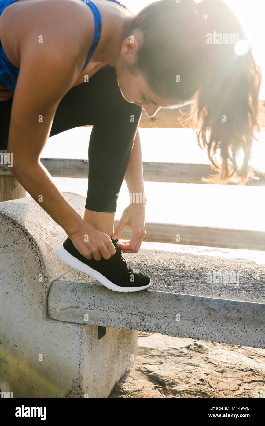 Young woman training on beach, tying trainer laces Stock Photo - Alamy