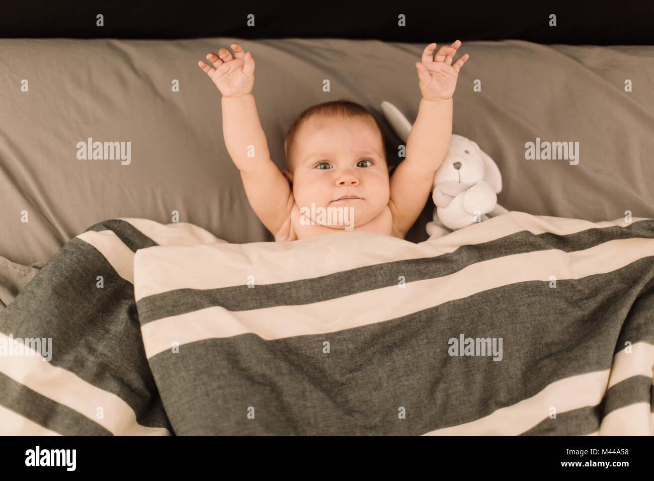 Portrait of baby girl lying in bed with arms raised, overhead view Stock Photo - Alamy