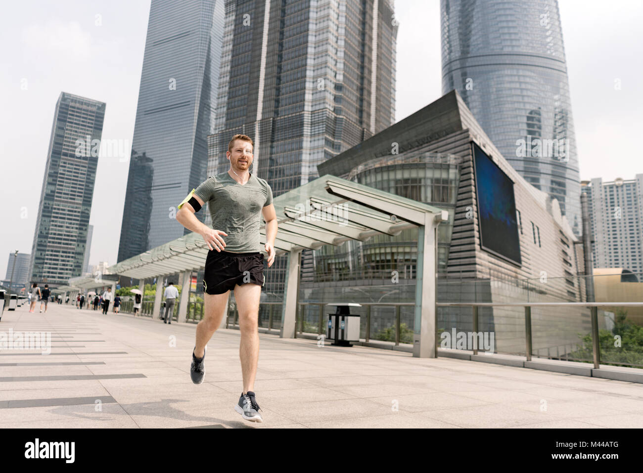 Young male runner running in Shanghai financial centre, Shanghai, China ...