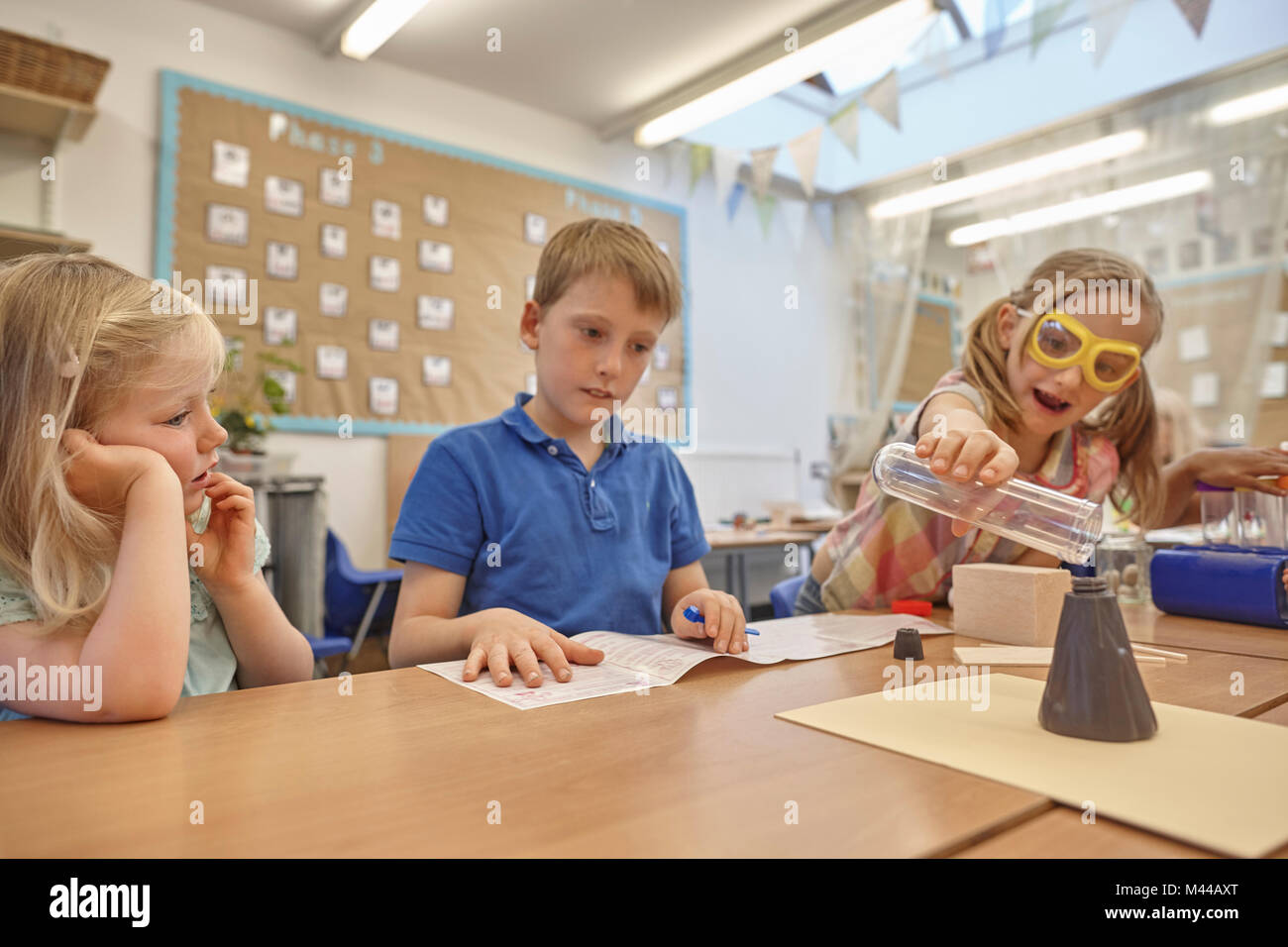 Primary schoolgirls and boy doing experiment at classroom desk Stock ...
