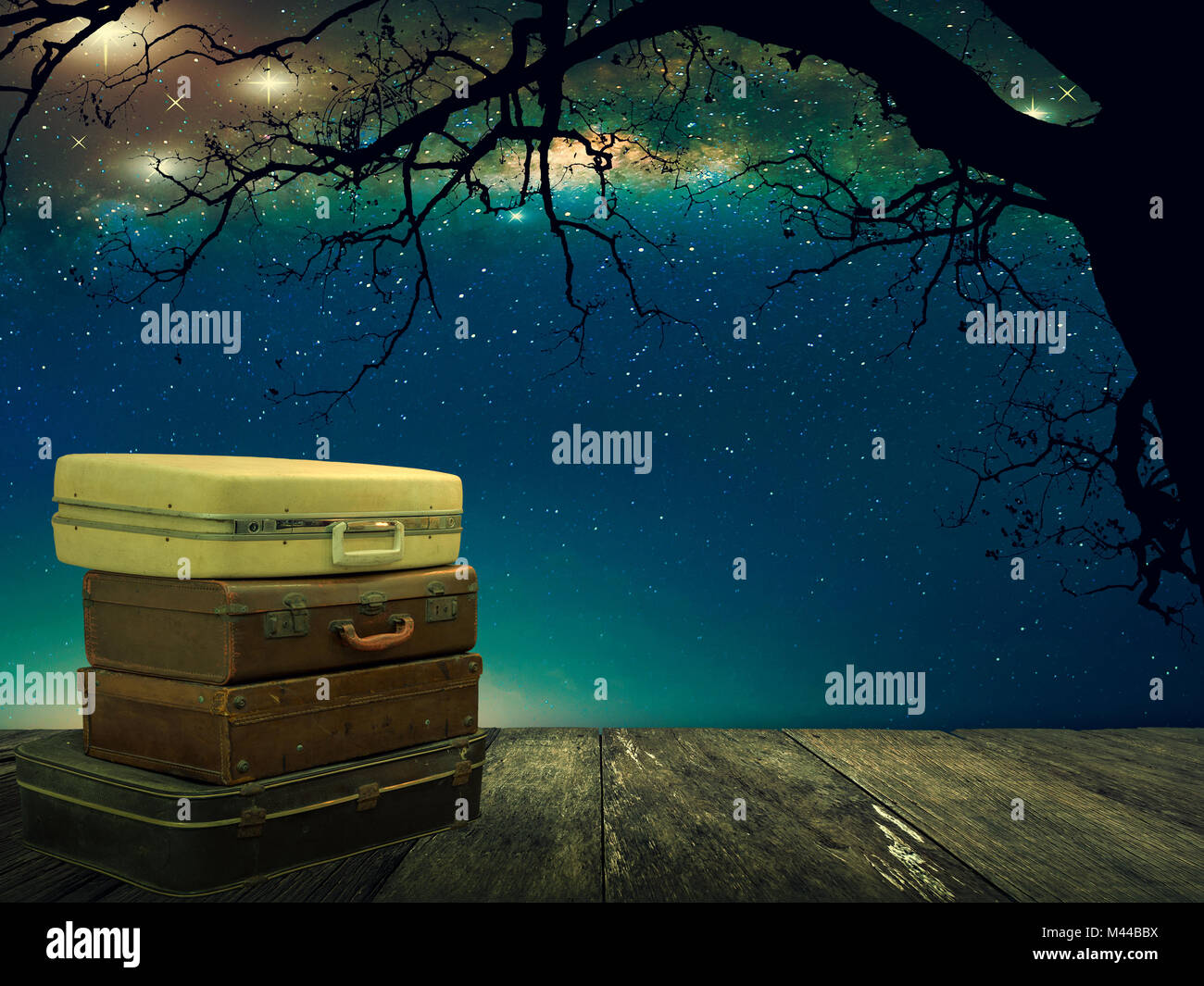 Stacked leather luggage on wood plank with stars in night sky ...