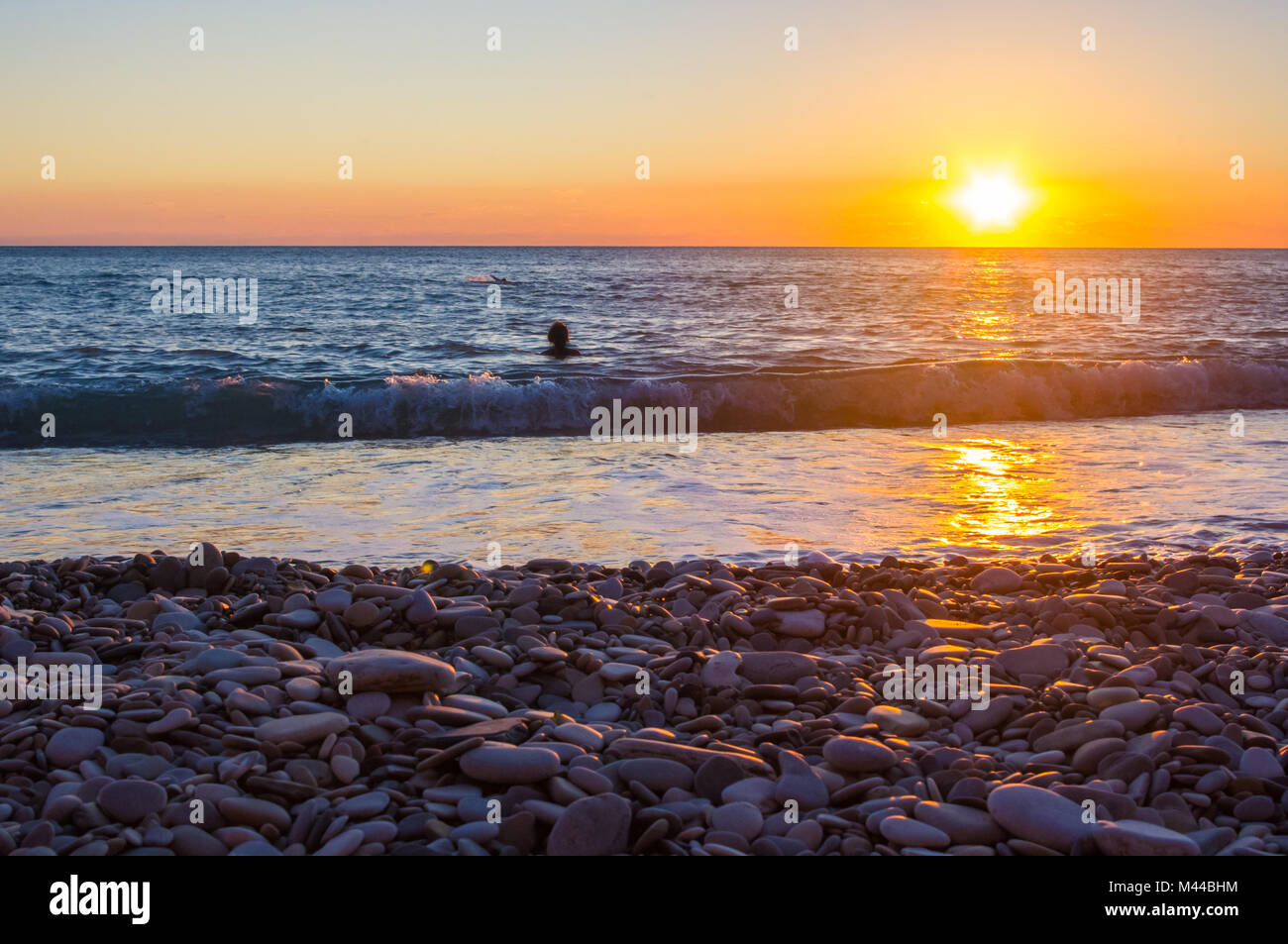 Summer sea sunset on the pebble beach, the sun, waves and clouds ...