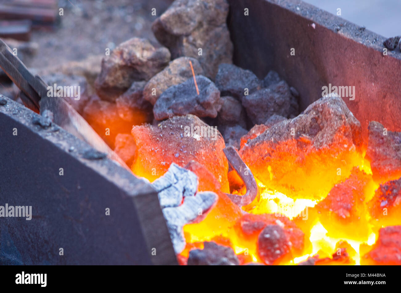 blacksmith furnace with burning coals, tools, and glowing hot metal ...