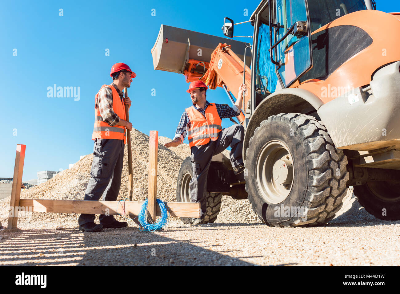 Workers on construction site discussing the use of tools Stock Photo ...