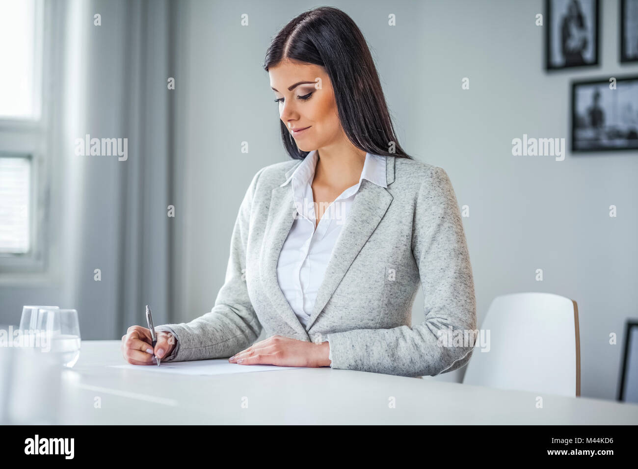 Beautiful young businesswoman writing on document in office Stock Photo ...