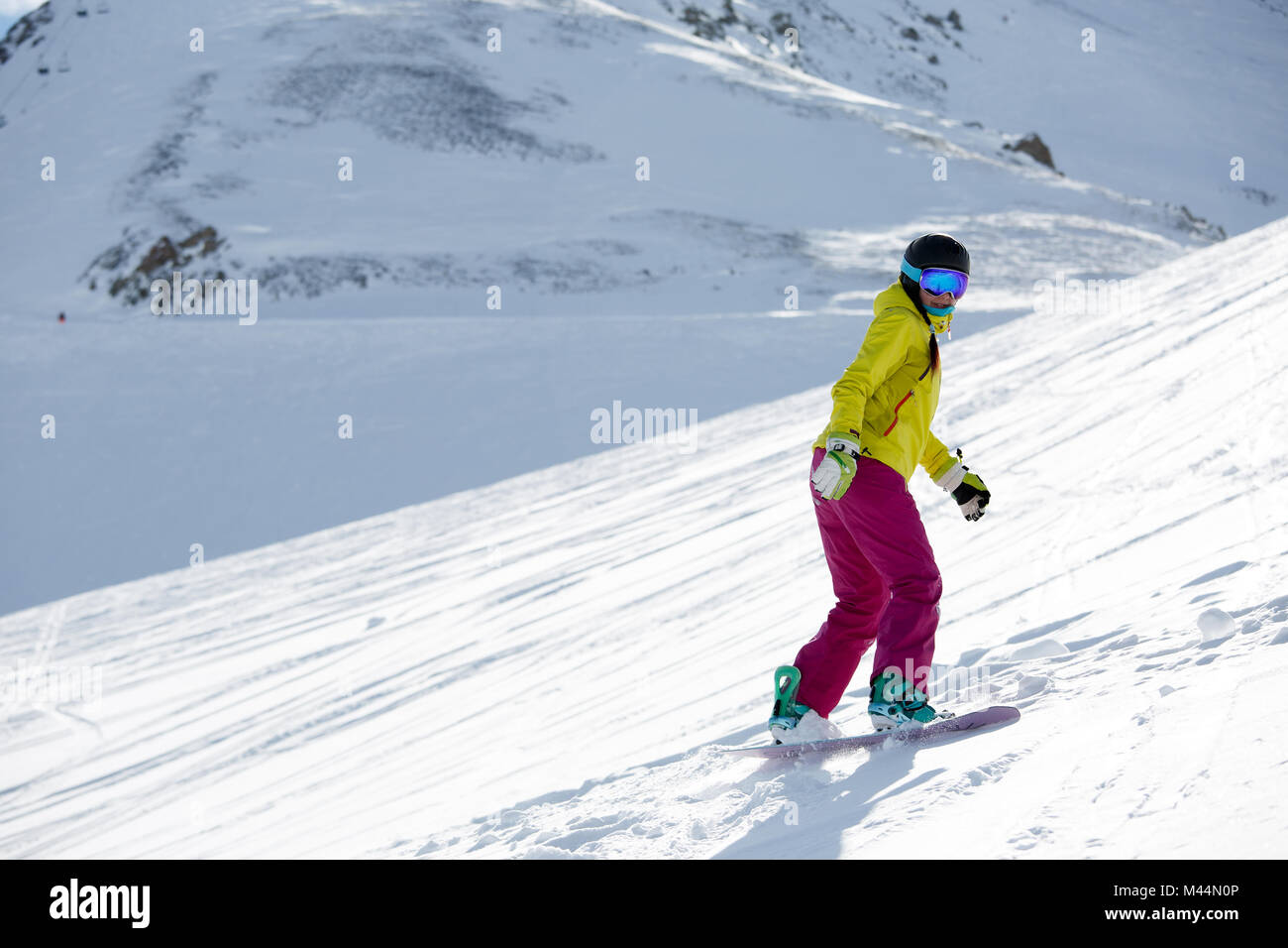 Photo of female athlete wearing helmet and mask, snowboarding from ...