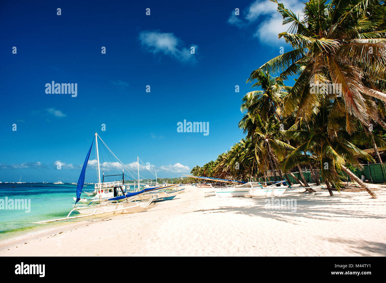 Tropical beach with palm trees, pilippine boats, blue sky, turquoise ...