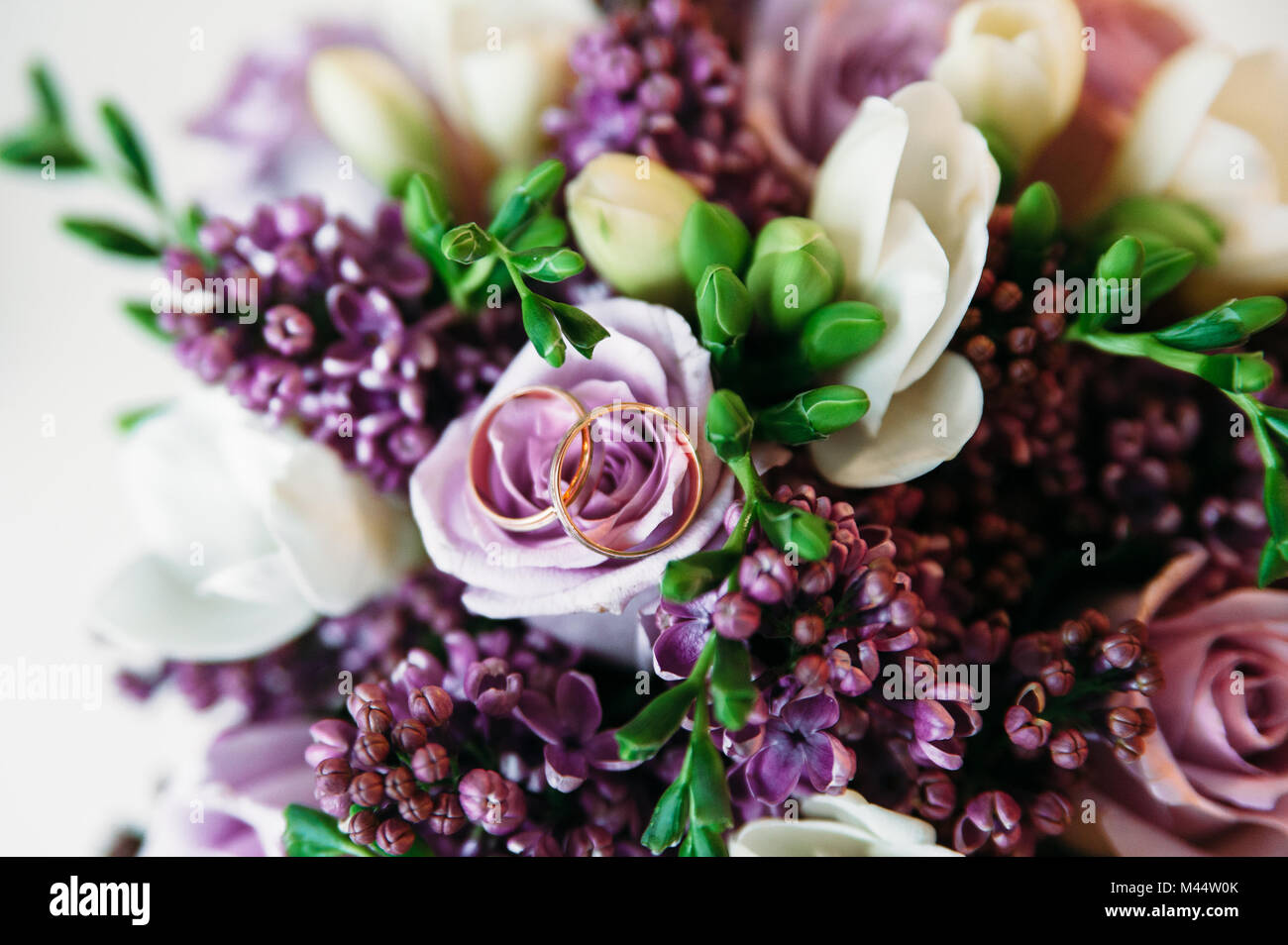 Wedding golden rings on wedding bouquet with lilac and white roses ...