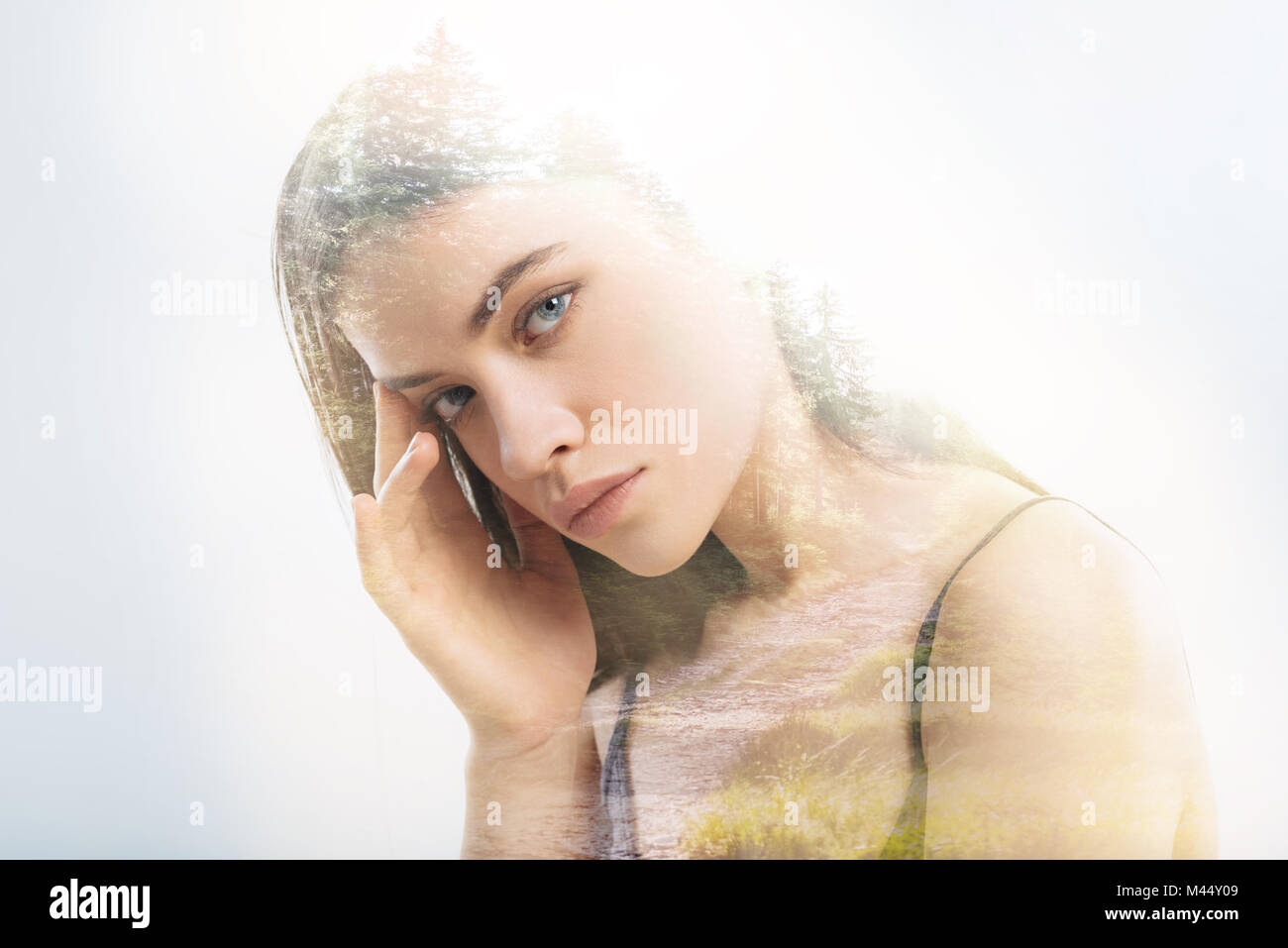 Beautiful woman touching her temple while thinking Stock Photo - Alamy