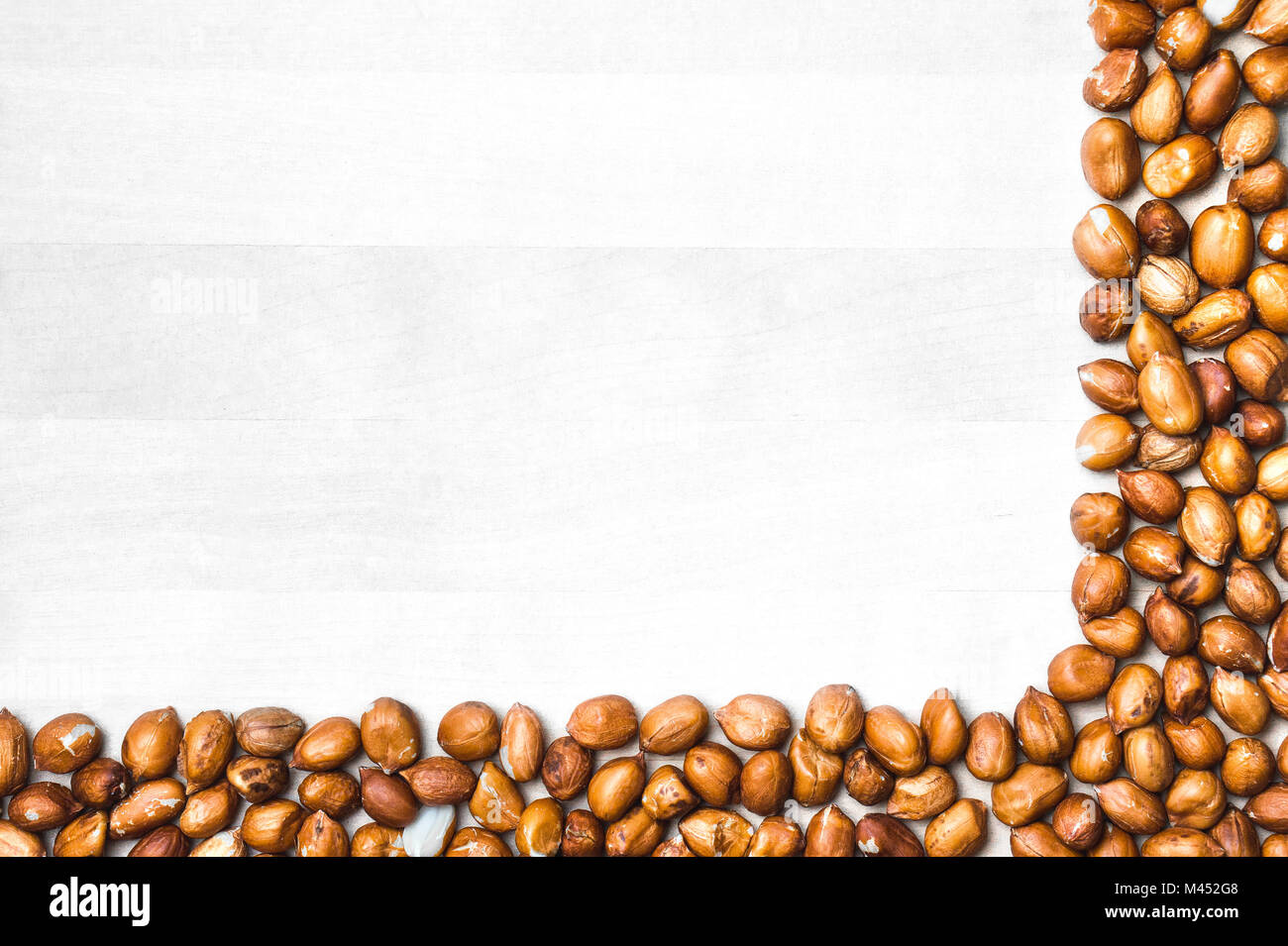Peanut corner background. White wooden board or table with nut frame or ...