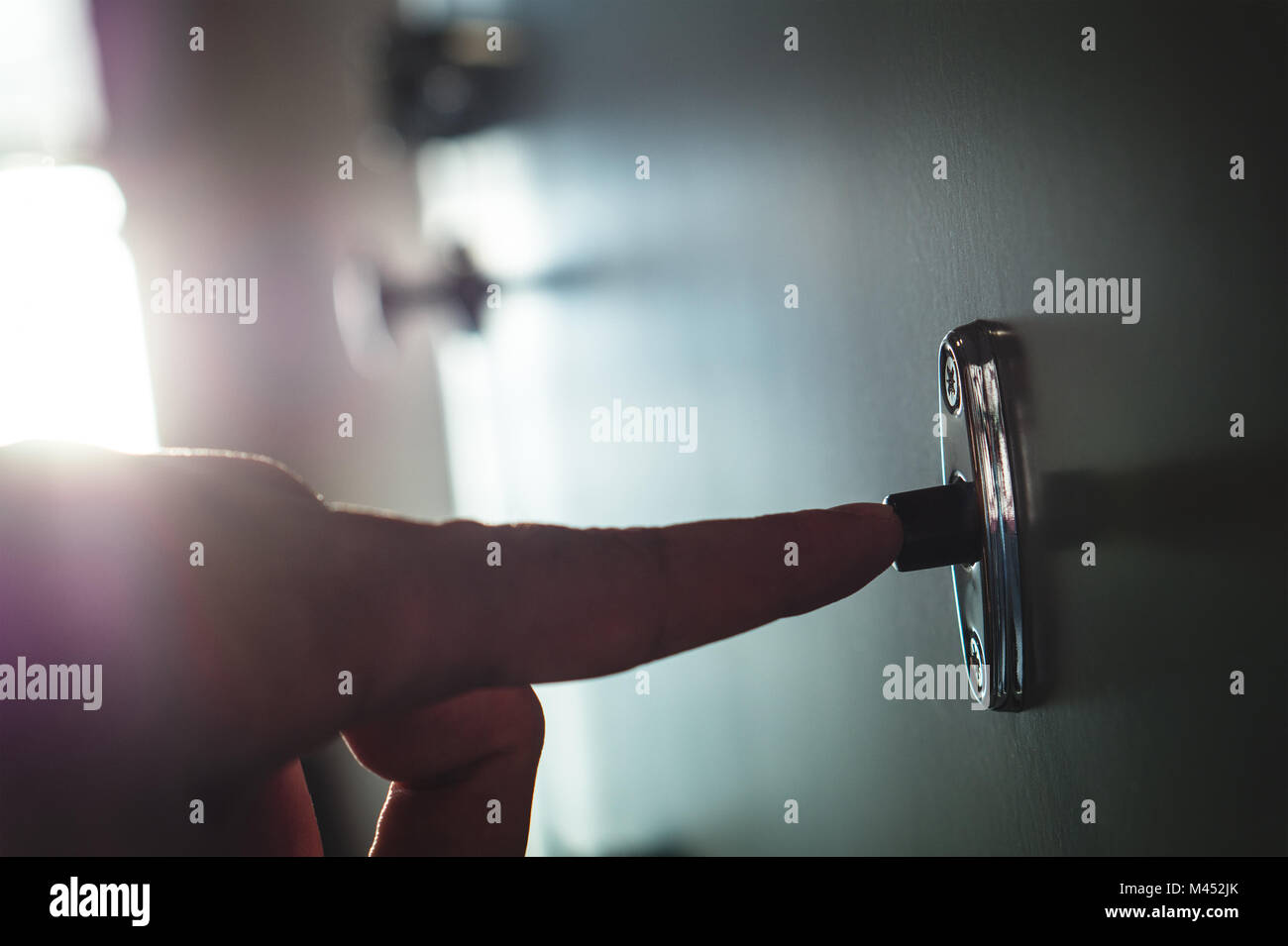 Finger pressing doorbell in apartment building corridor. Close up of ...