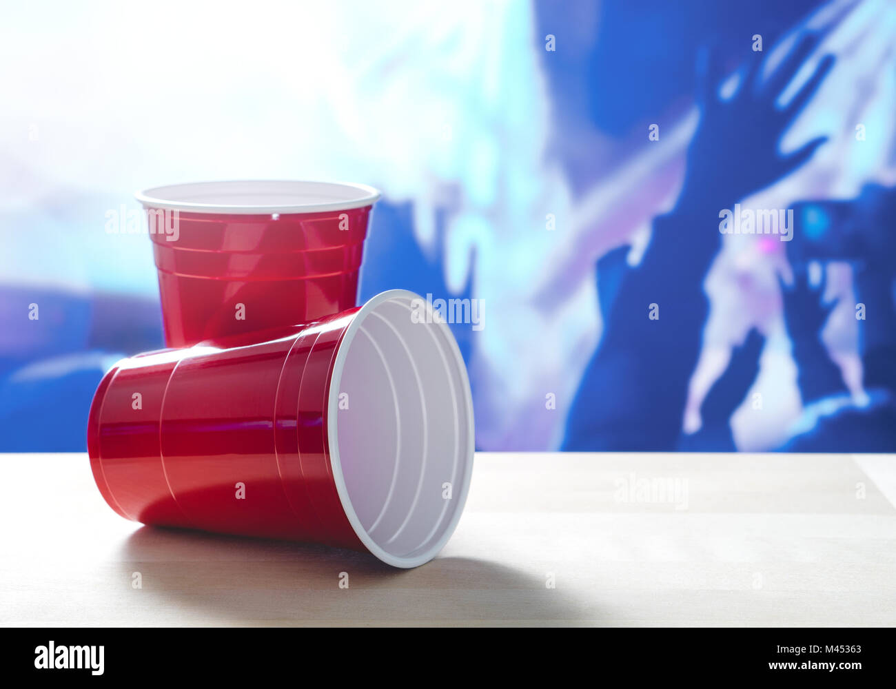2 plastic red party cups on a table. One on its side. Nightclub or ...