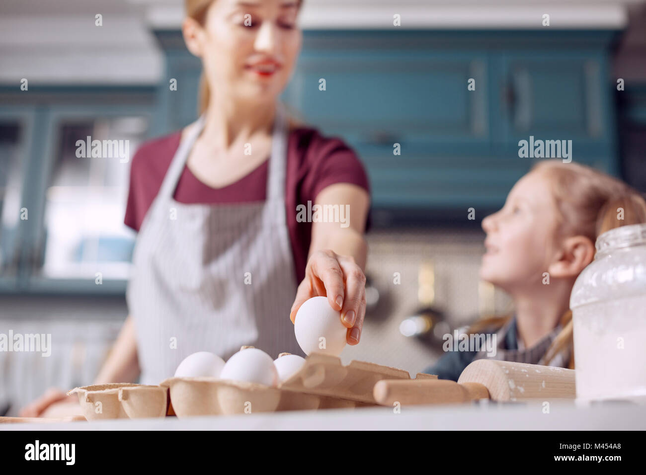 Young woman taking egg and chatting with daughter Stock Photo - Alamy