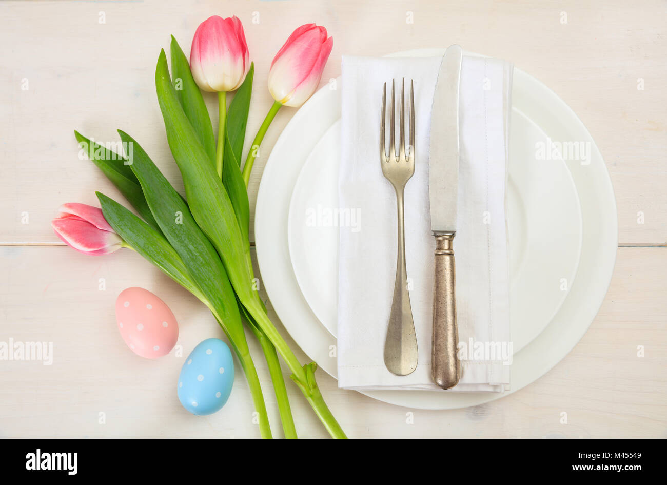 Easter table setting with pink tulips on white wooden background. Top ...