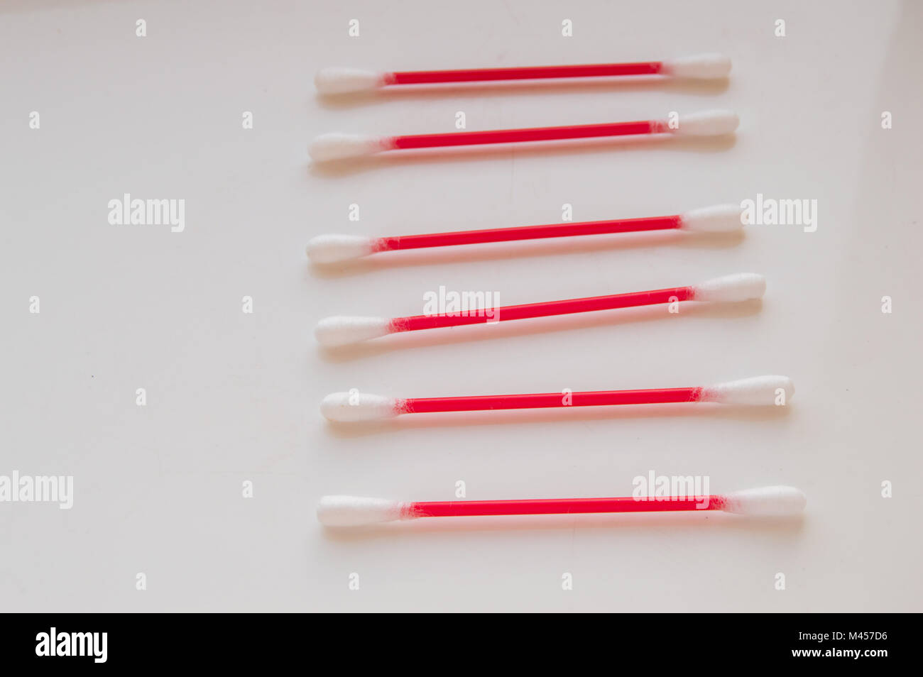 Cotton swabs lie in rows on a white background. Red plastic sticks for ...