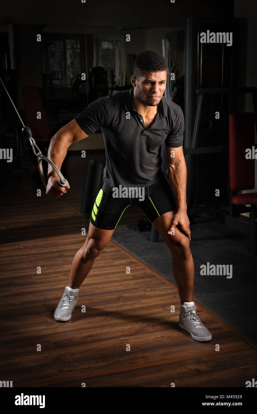 Young man doing one arm standing high cable fly Stock Photo - Alamy