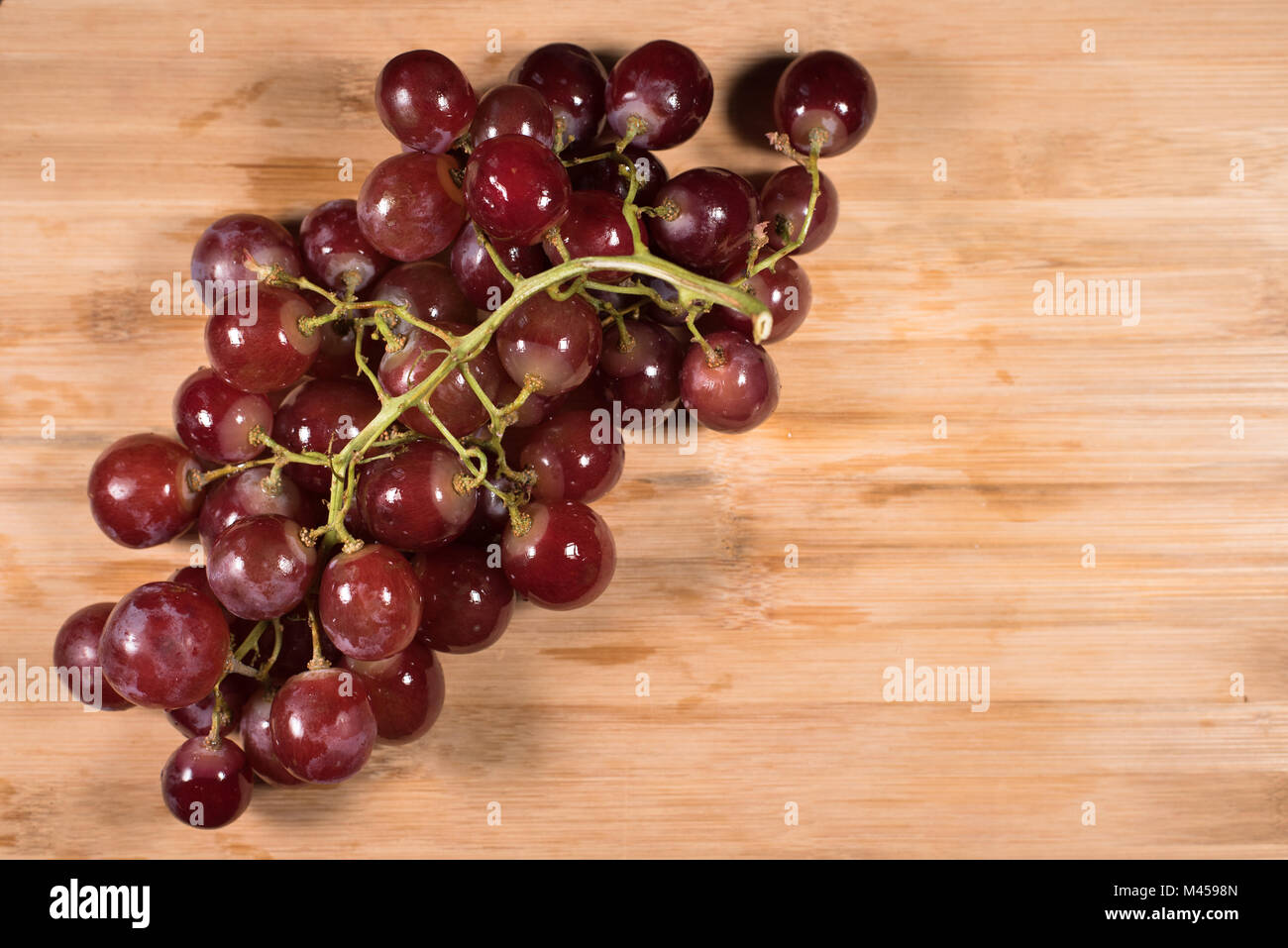 red grapes with stalks on wooden board background. red fresh grapes ...