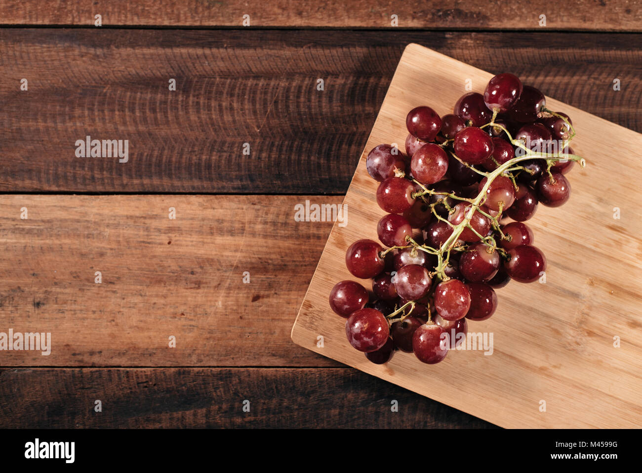 red grapes with stalks on wooden board background. red fresh grapes ...