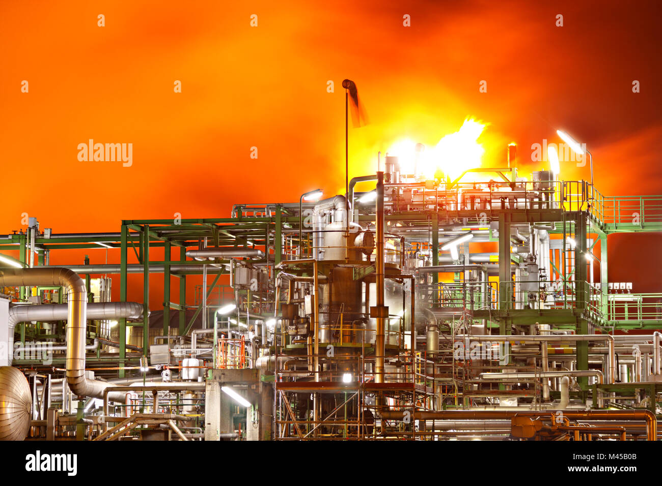 A small fire burning in a refinery behind some industrial buildings ...