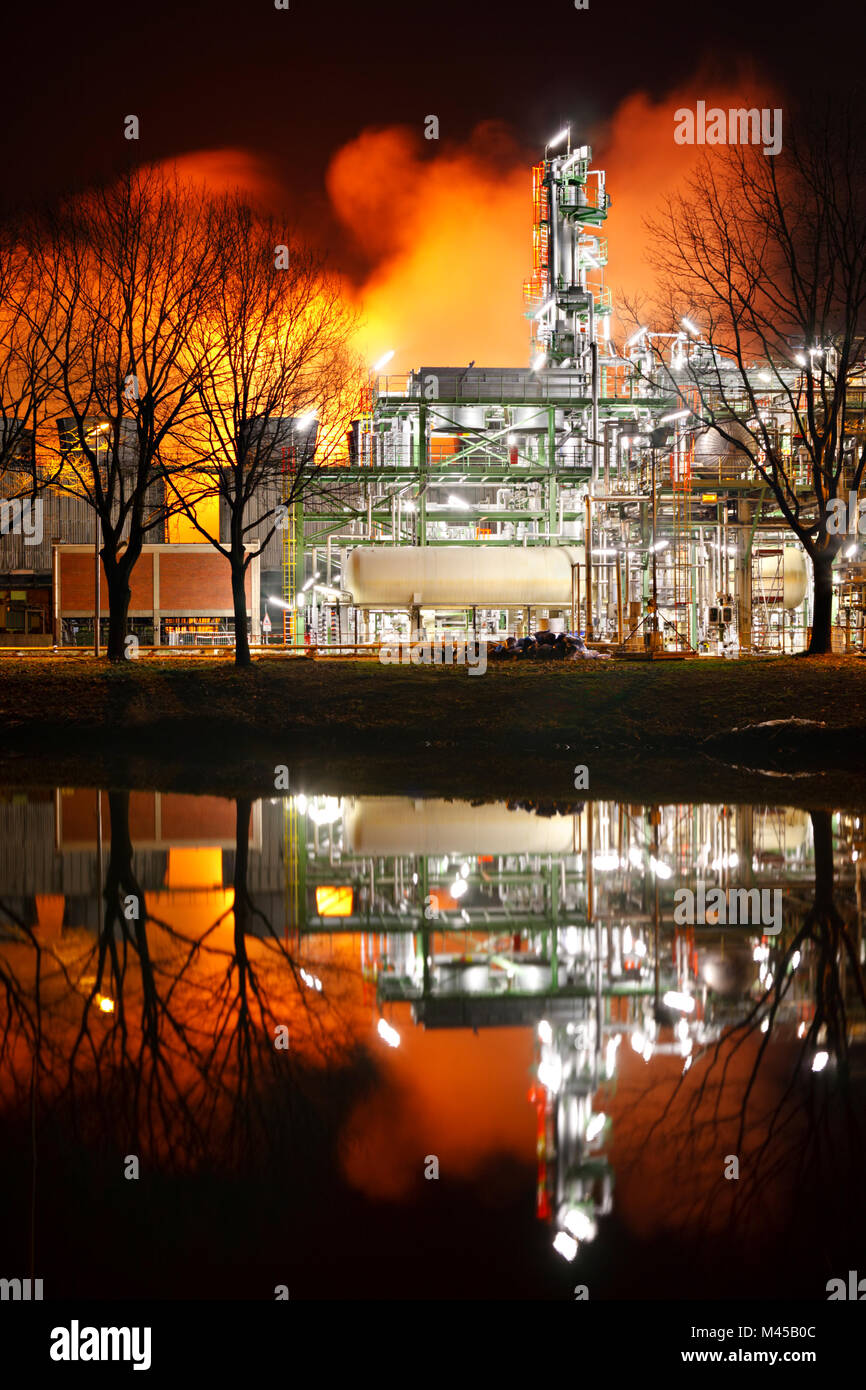 Distillation Tower of an oil refinery with reflection at night. The ...