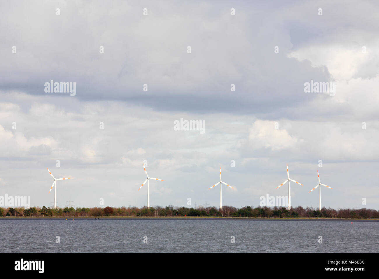 A row of wind turbines behind a lake Stock Photo - Alamy
