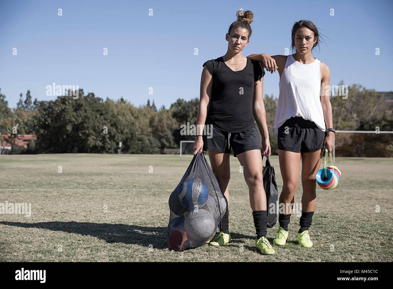 Women on football pitch carrying footballs in net sack Stock Photo - Alamy