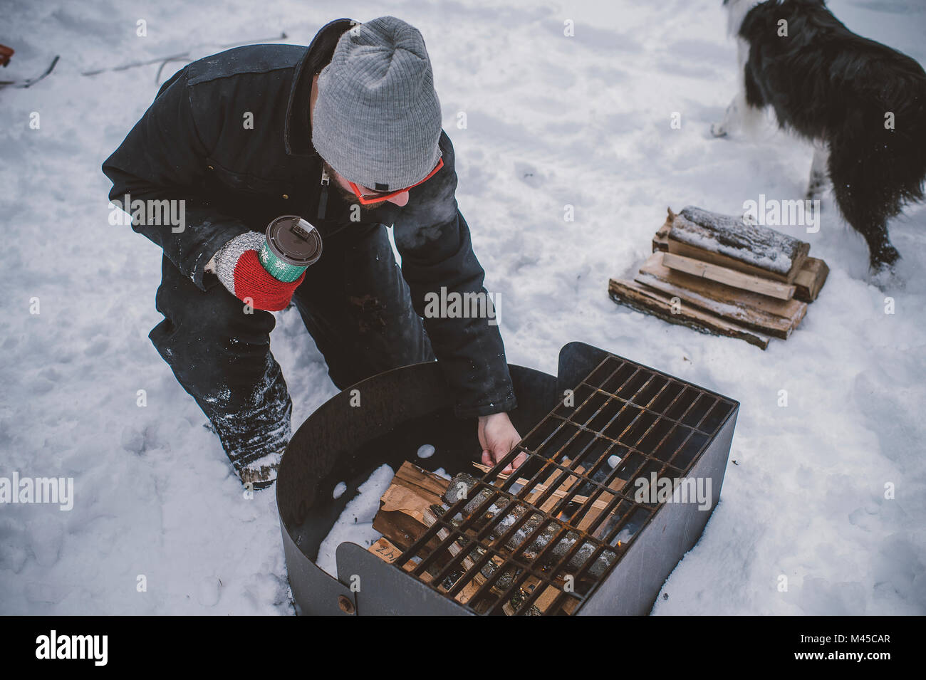 Young man preparing to light barbecue fire in snow Stock Photo - Alamy