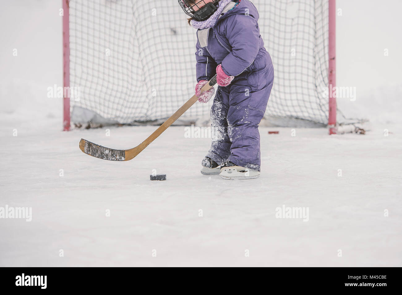Young girl playing ice hockey, preparing to hit puck, mid section Stock ...