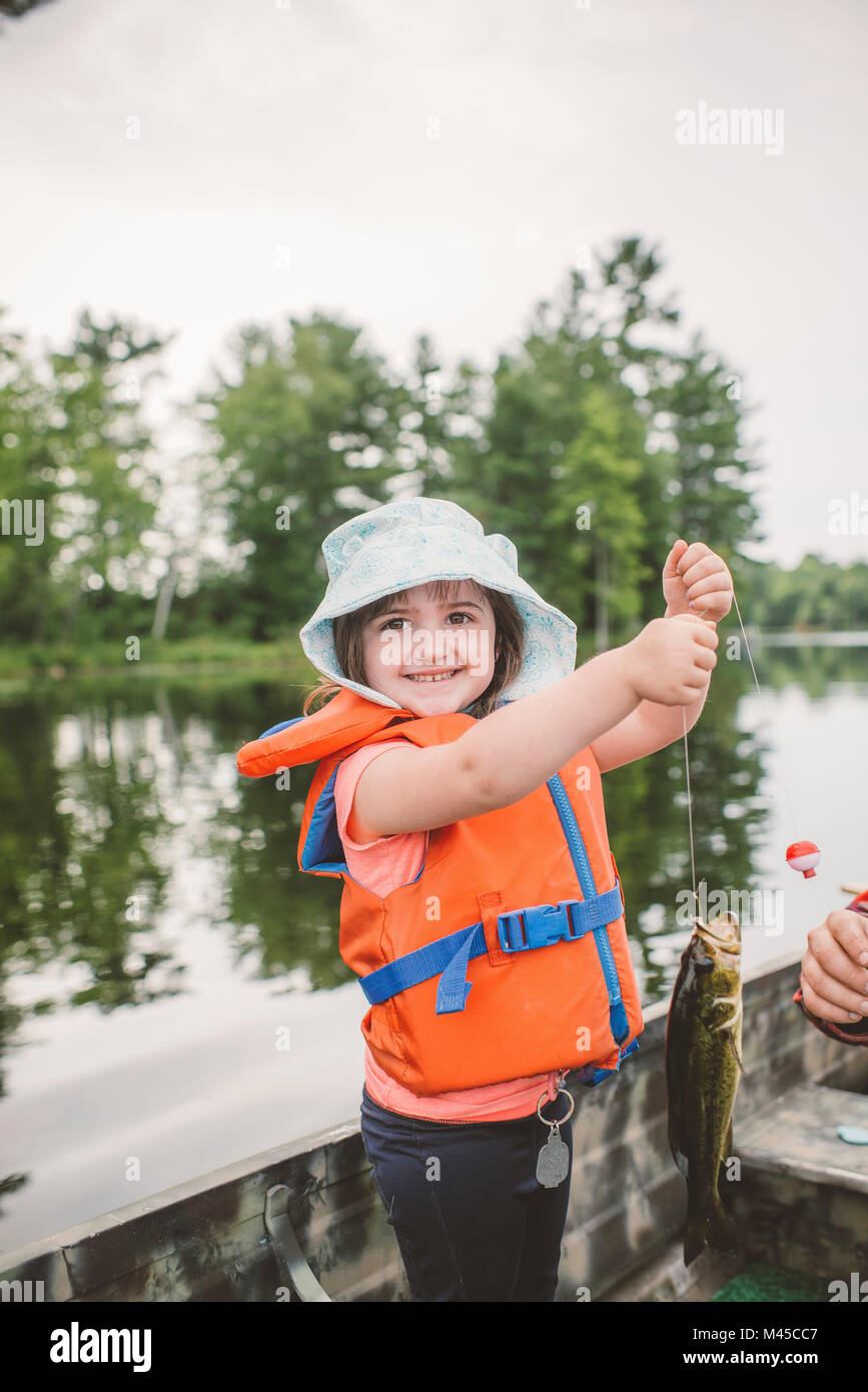 Father and daughter in boat on lake, daughter holding caught fish on ...