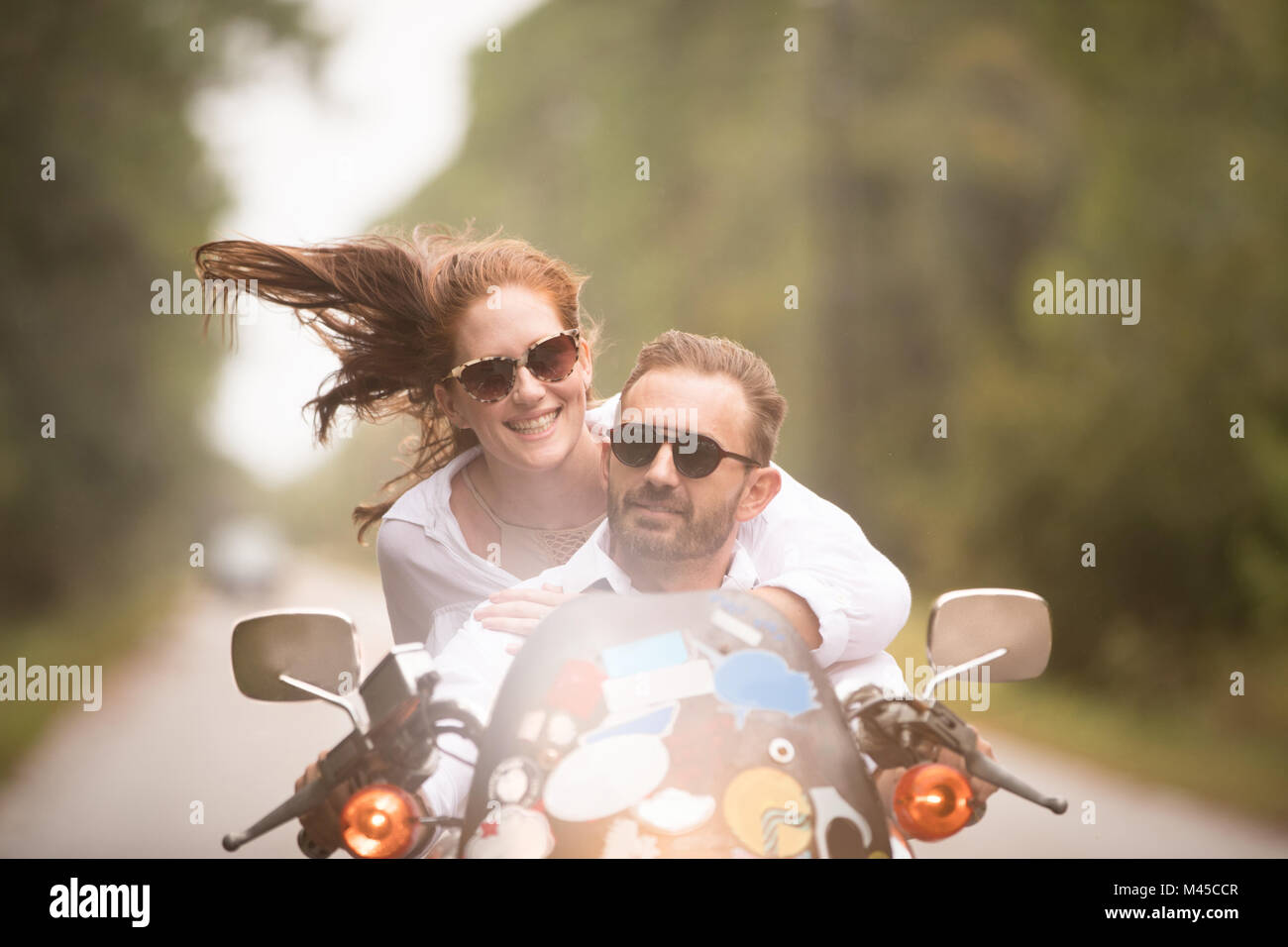 Couple riding on motorbike Stock Photo - Alamy
