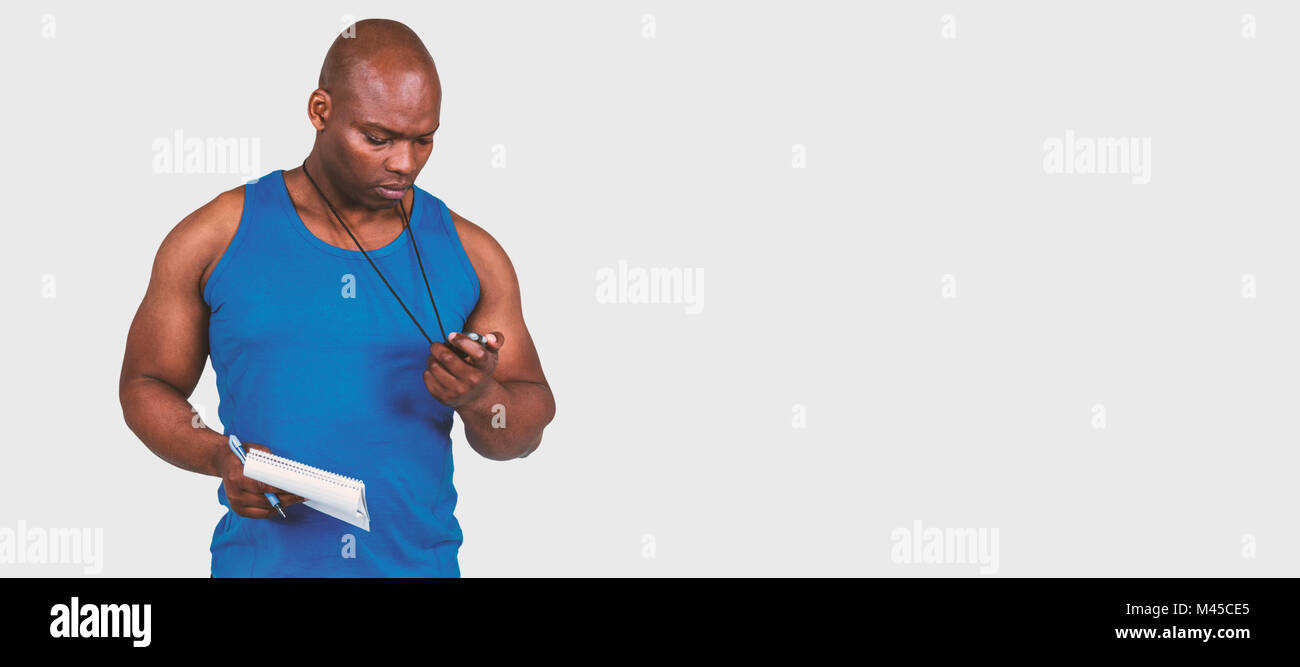 Composite image of fit trainer checking his stopwatch Stock Photo - Alamy