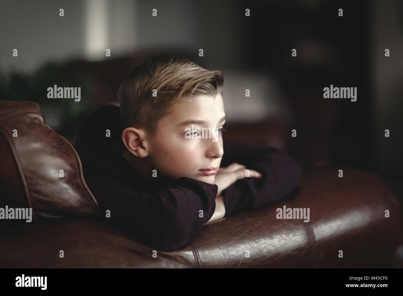 Boy relaxing on leather sofa Stock Photo - Alamy