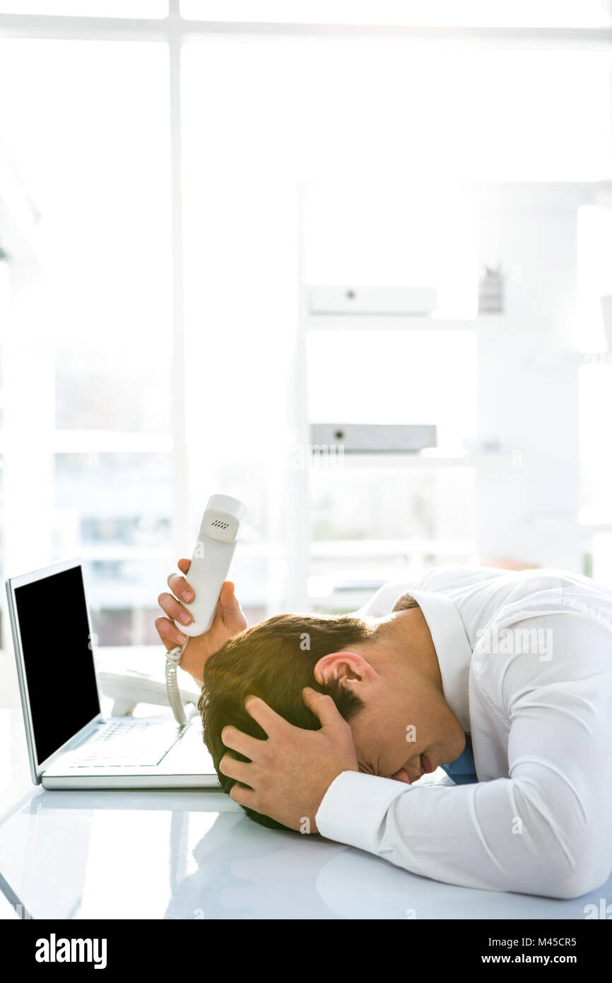 Overwhelmed asian businessman answering the phone Stock Photo - Alamy