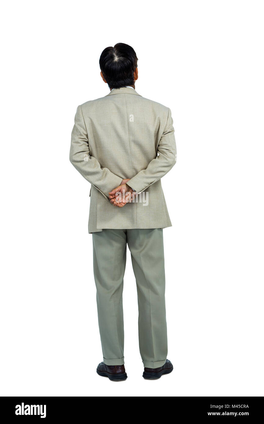 Businessman standing and looking with hands behind back Stock Photo - Alamy
