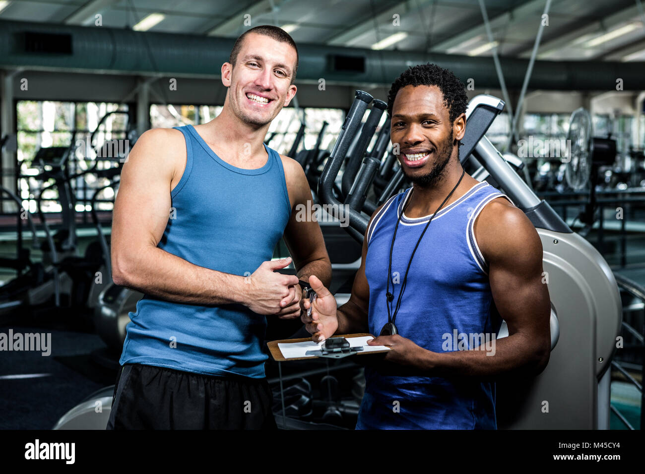 Muscular man discussing performance with trainer Stock Photo - Alamy