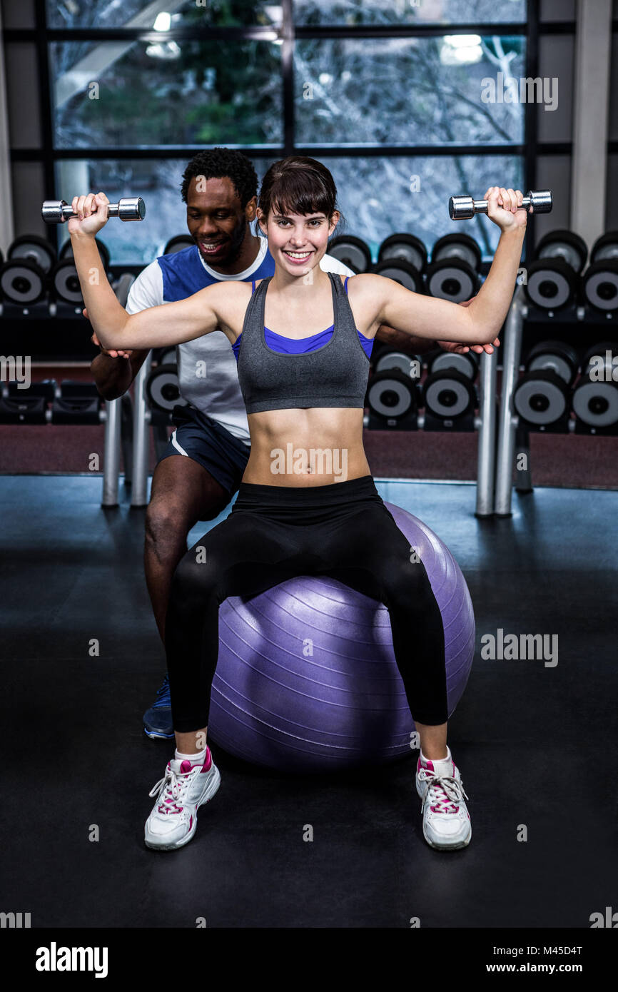 Male trainer helping woman during dumbbells exercise Stock Photo - Alamy