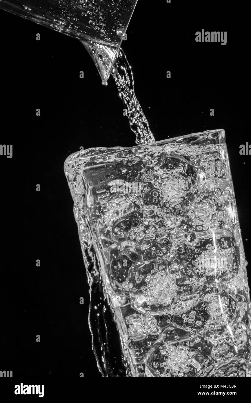 sparkling water overflow over ice cubes Stock Photo - Alamy