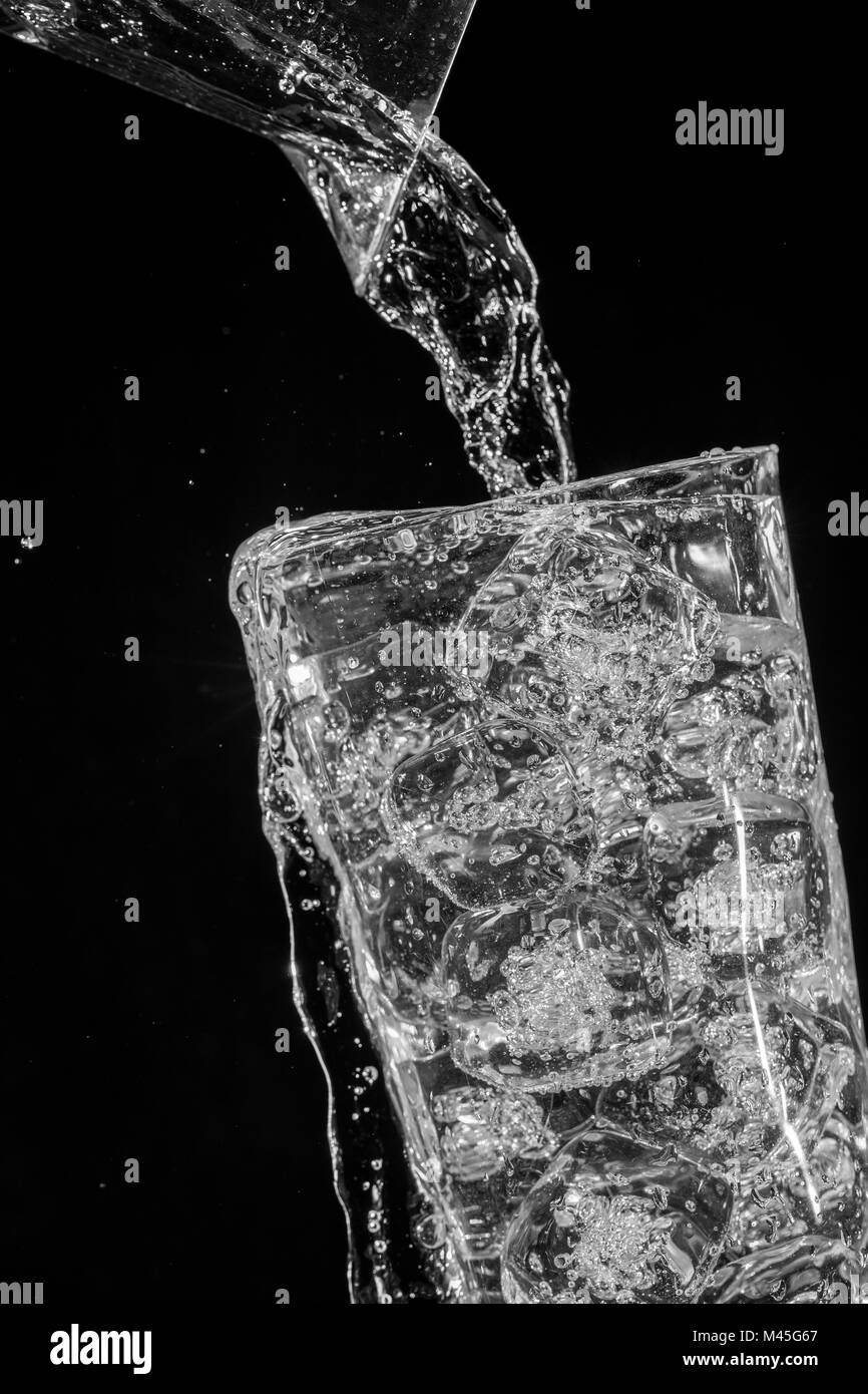 sparkling water overflow over ice cubes Stock Photo - Alamy