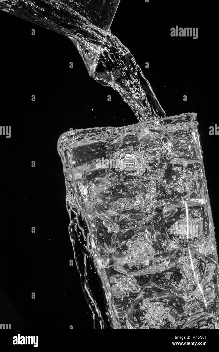 sparkling water overflow over ice cubes Stock Photo - Alamy
