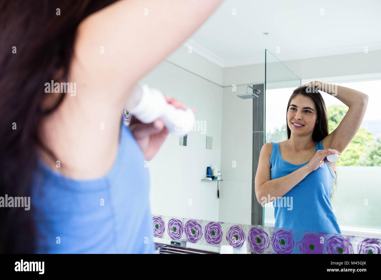 Smiling brunette putting deodorant on her armpit Stock Photo - Alamy
