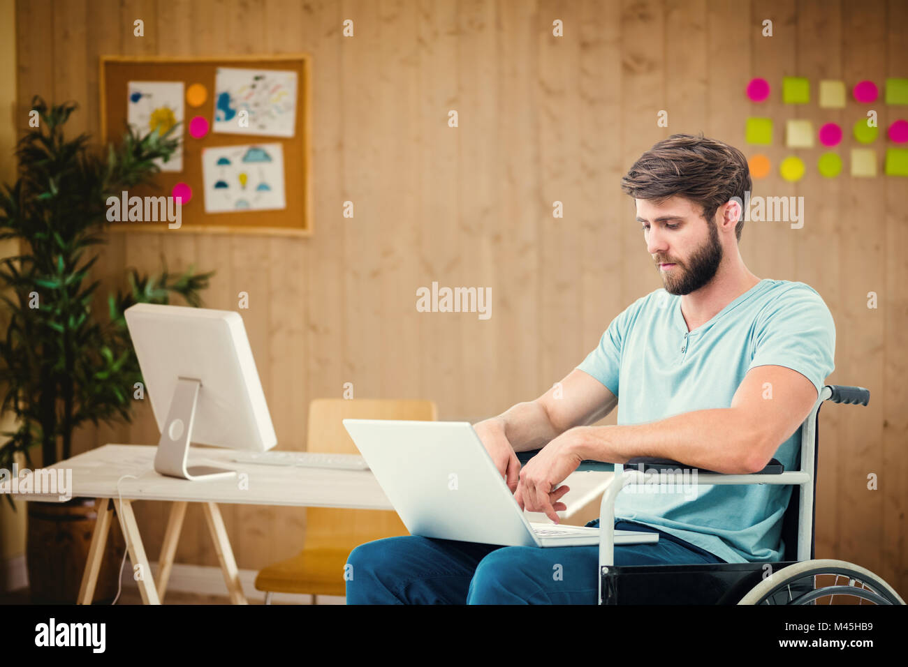 Composite image of man in wheelchair using computer Stock Photo - Alamy