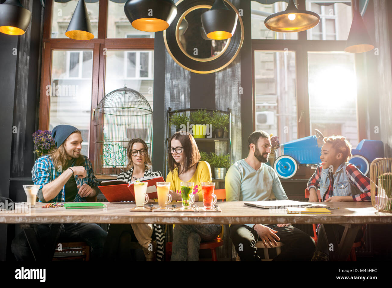 Friends sitting in the modern cafe Stock Photo - Alamy