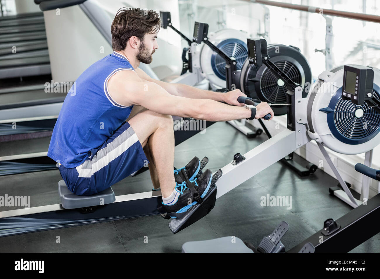 Handsome man doing exercise on drawing machine Stock Photo - Alamy