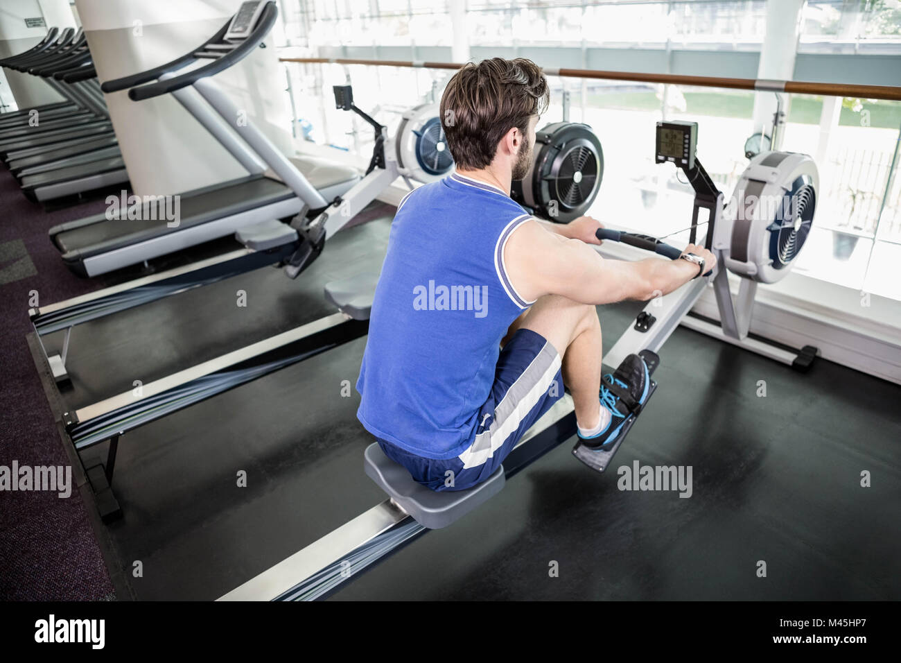 Handsome man doing exercise on drawing machine Stock Photo - Alamy