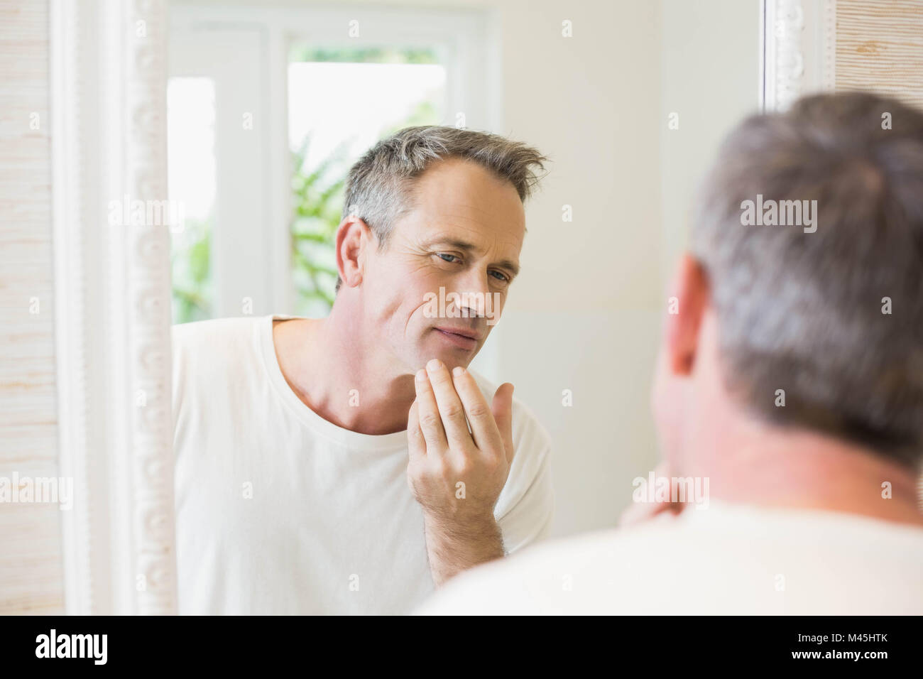 Handsome man looking at himself in the mirror Stock Photo - Alamy