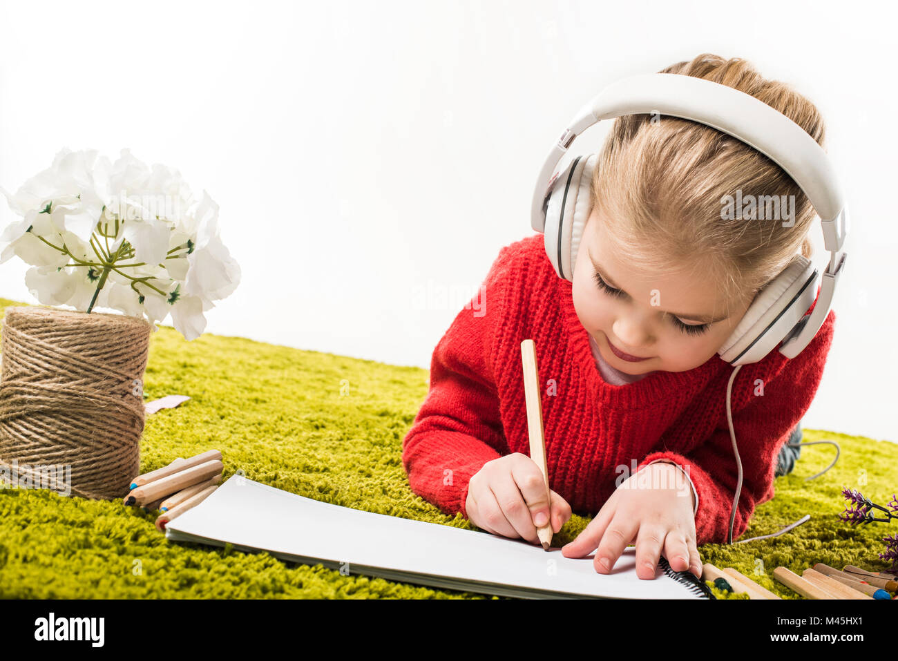 focused little child drawing with color pencils and listening music on ...