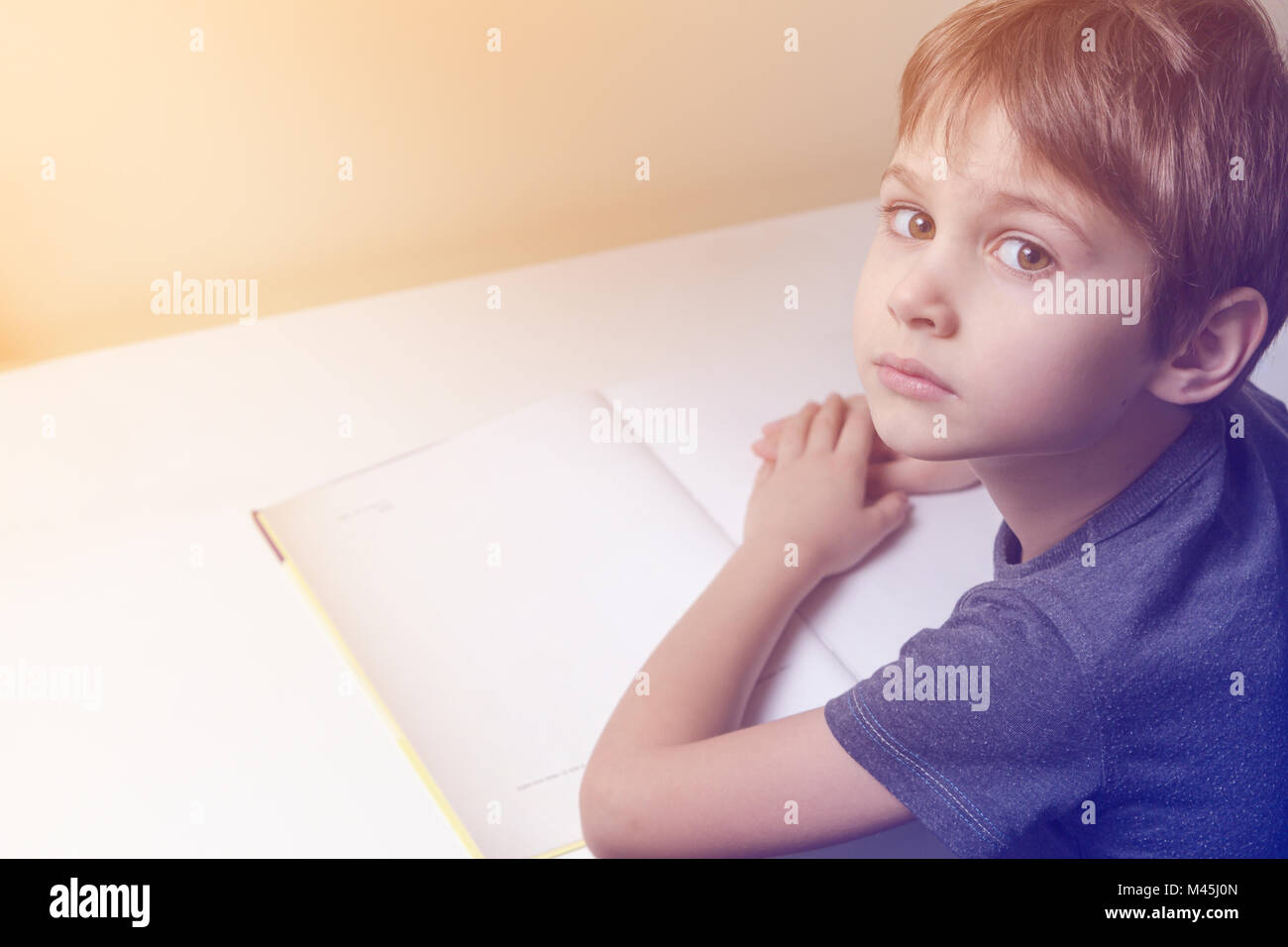 Child sitting at the table, reading book and doing his homework Stock ...