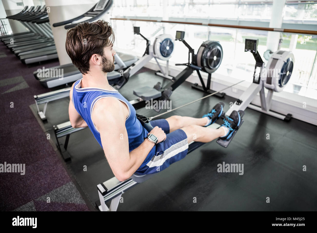 Handsome man doing exercise on drawing machine Stock Photo - Alamy